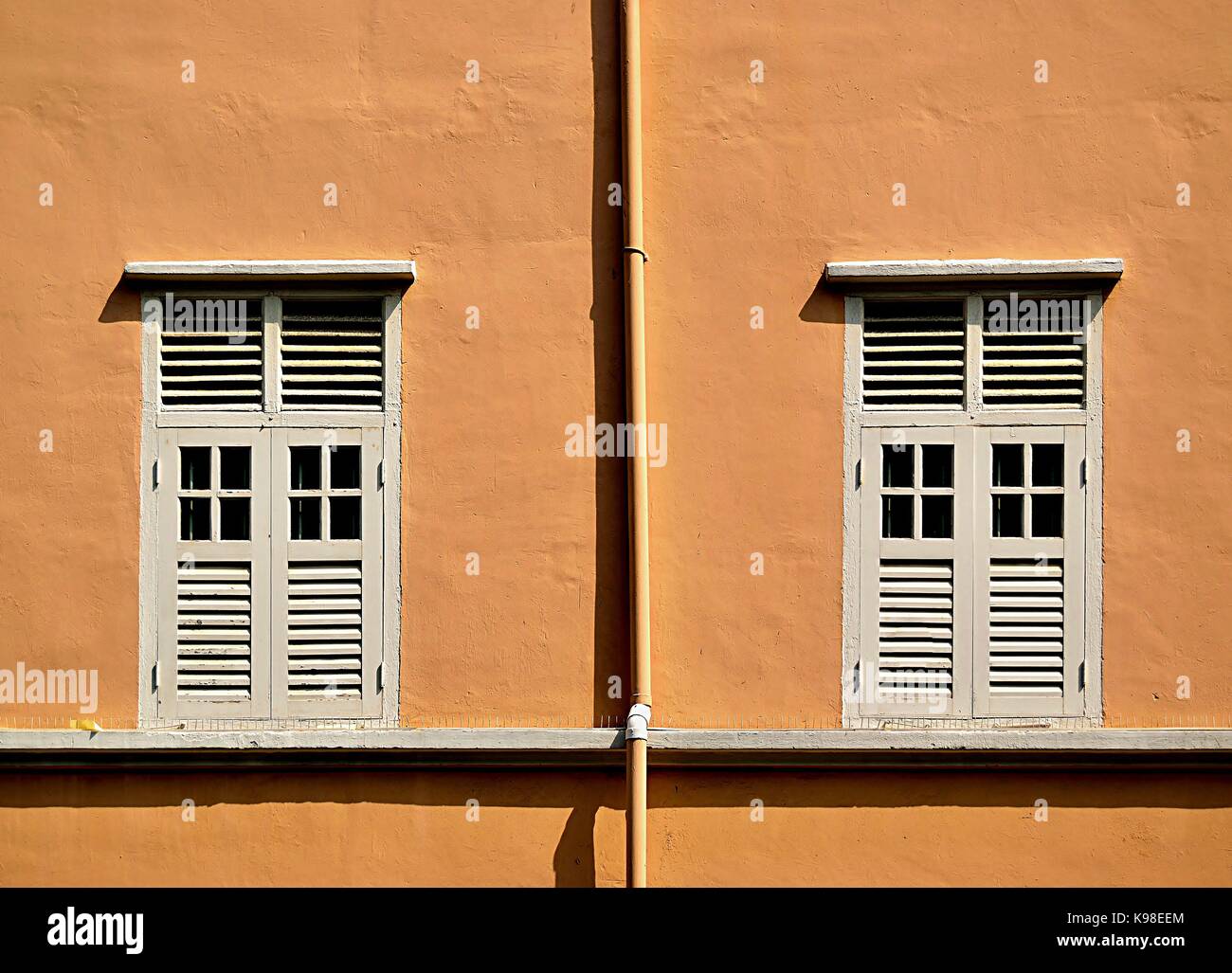 A pair of traditional windows with wooden shutters separated by a ...