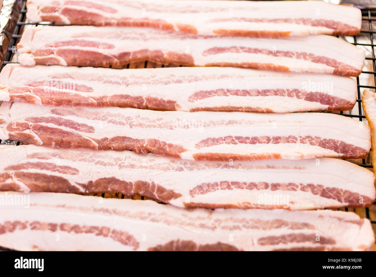 Raw bacon strips on a baking sheet Stock Photo - Alamy