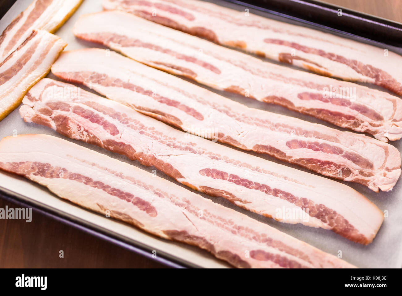 Raw bacon strips on a baking sheet Stock Photo - Alamy