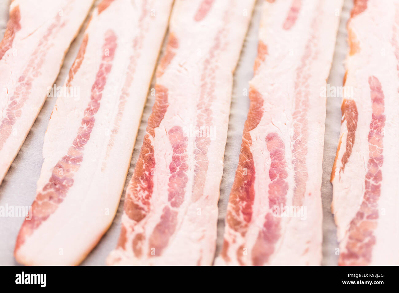 Raw bacon strips on a baking sheet Stock Photo - Alamy