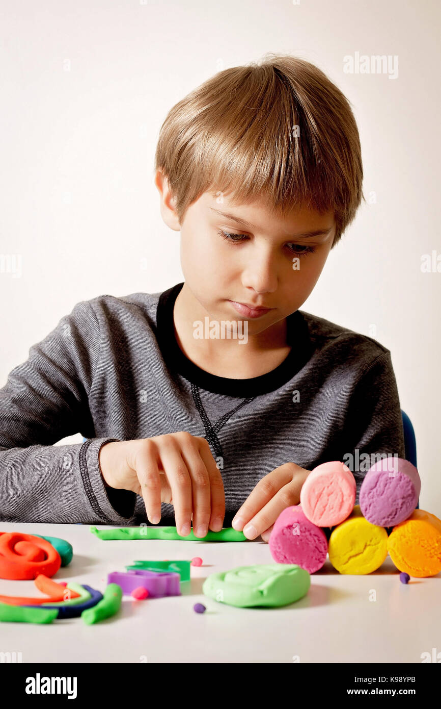 Boy playing and creating from modeling clay or plasticine Stock Photo ...