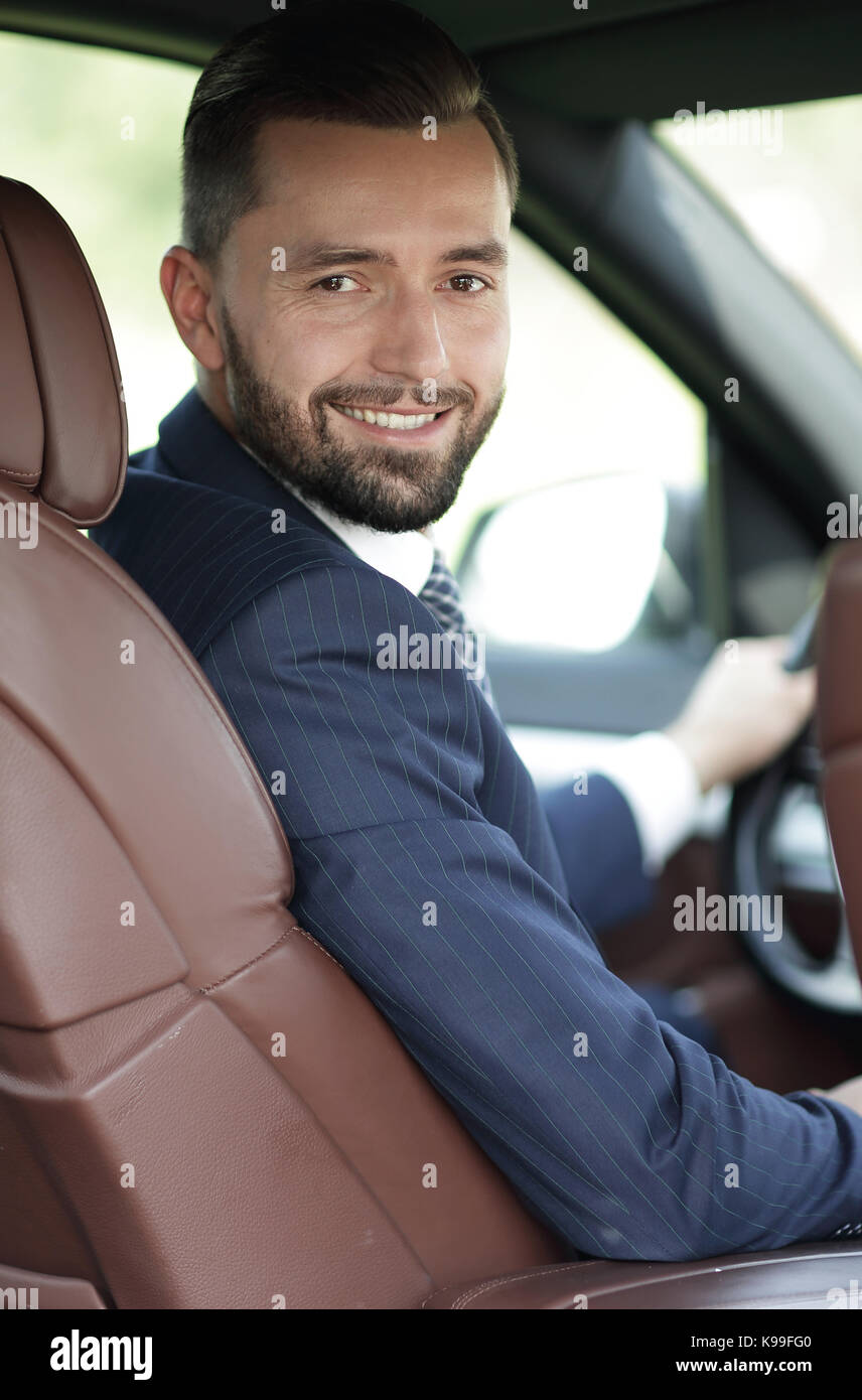 Handsome young man sitting in the front seat of a car looking at the ...