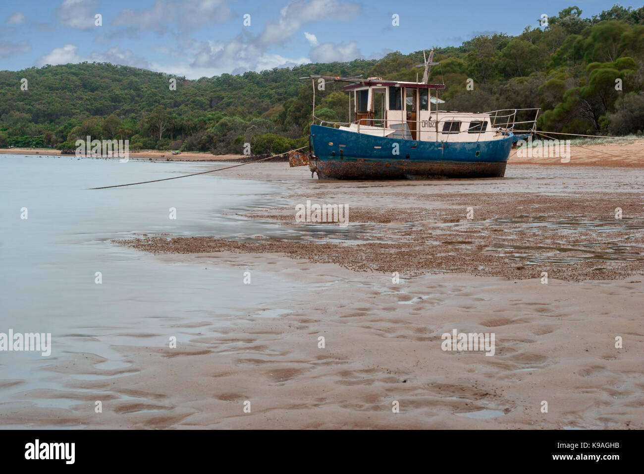 As the tide goes out, the fishing boat is left grounded on the sand ...