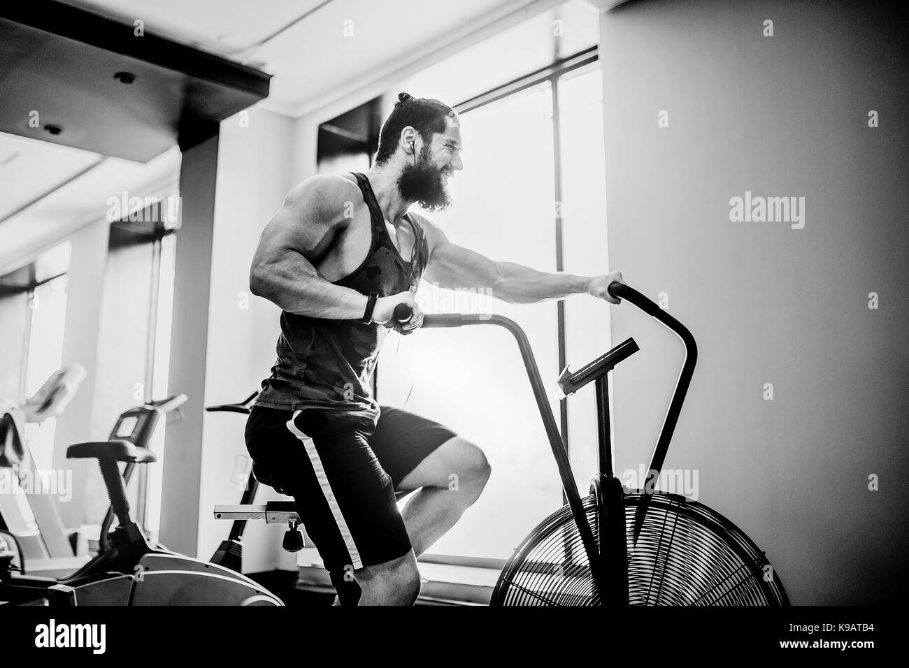 young man using exercise bike at the gym. Fitness male using air bike ...