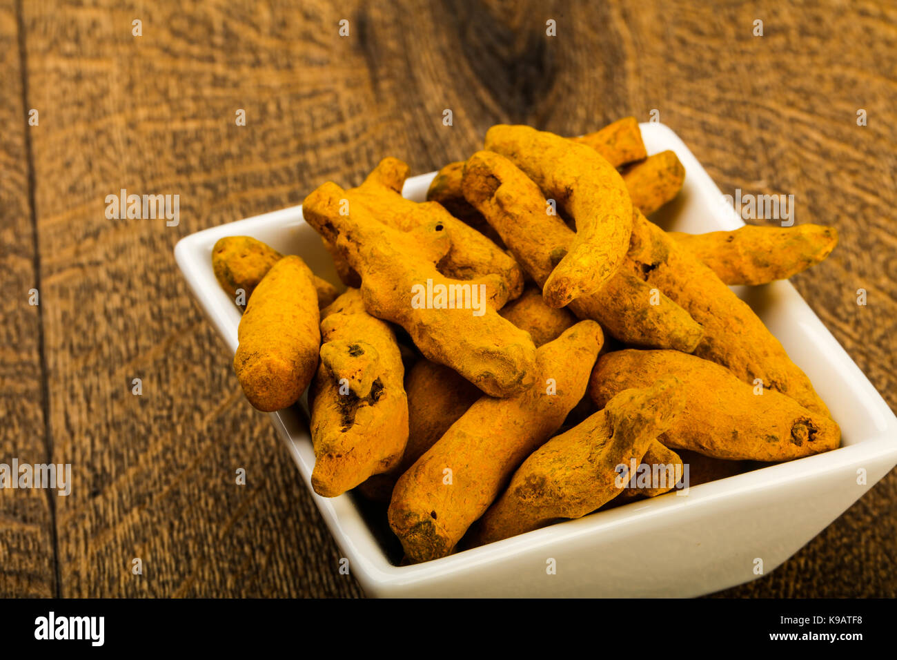 Tumeric roots heap in the bowl over wooden background Stock Photo - Alamy