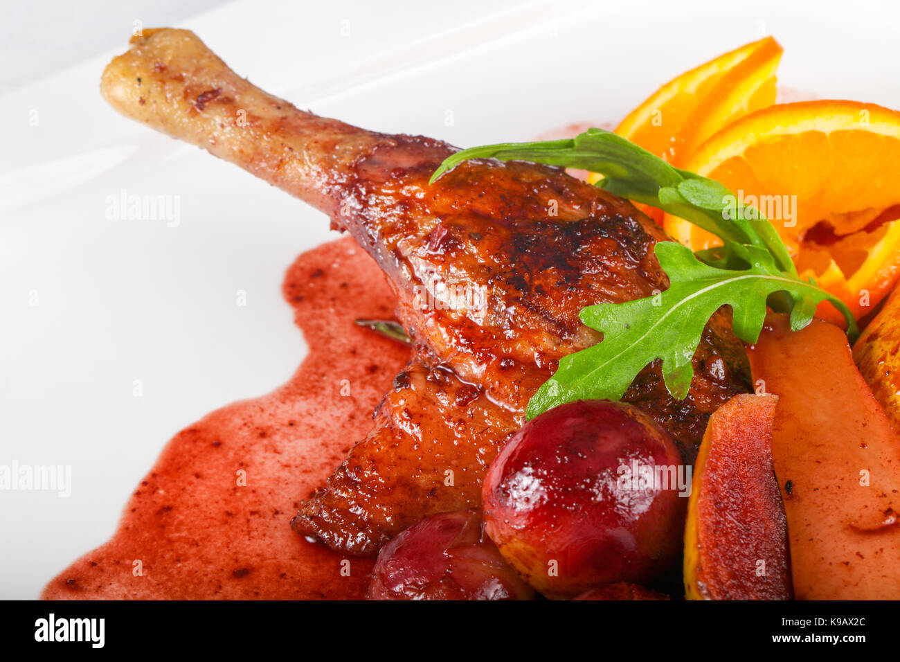 Duck leg with grape, orange and pear Stock Photo - Alamy