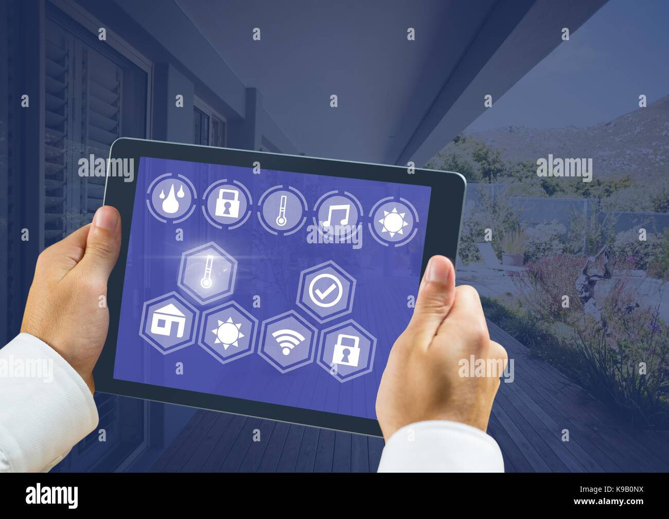 Digital composite of Hand holding tablet with smart home interface at ...