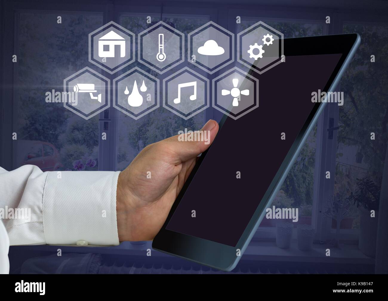 Digital composite of Hand holding tablet with smart home interface at ...