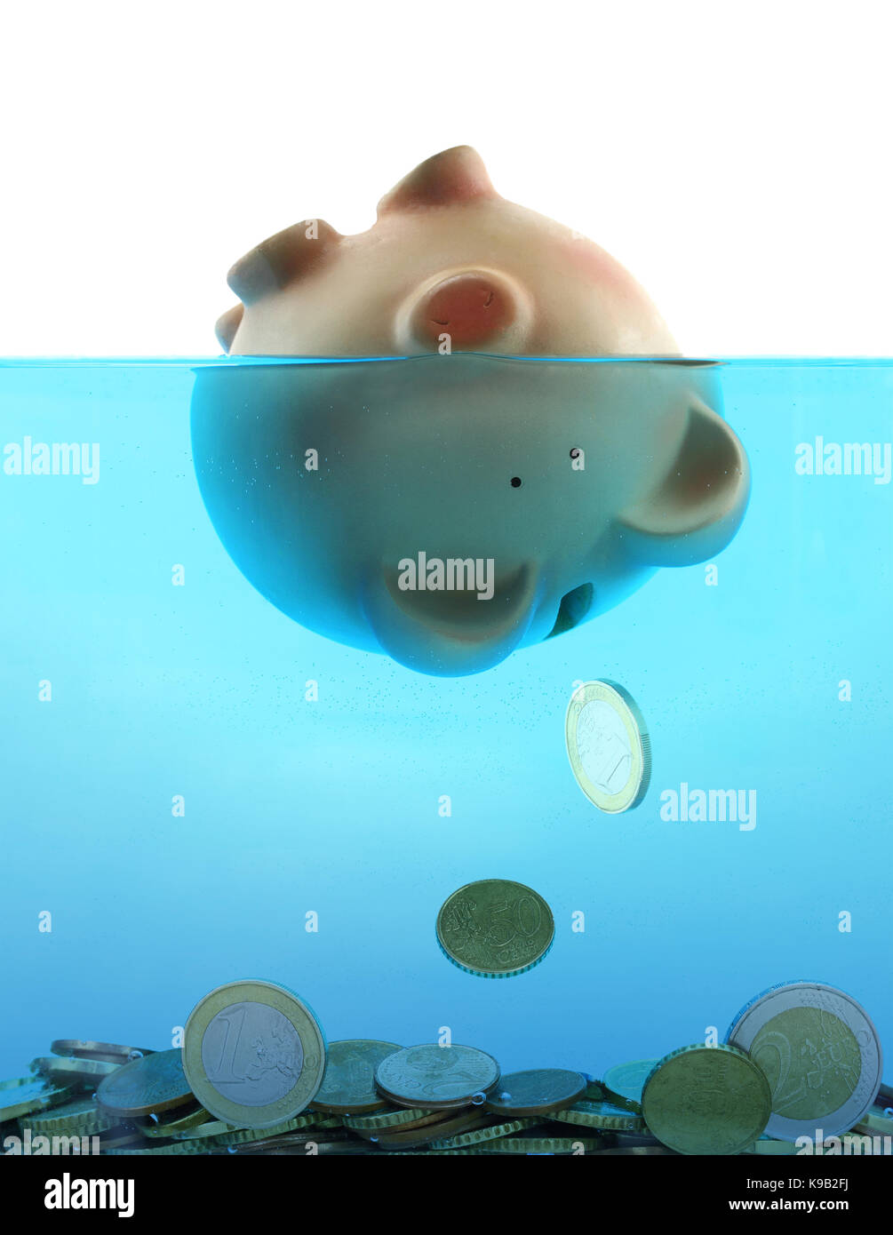 Drowning in debt represented by a piggy bank sinking in blue water ...