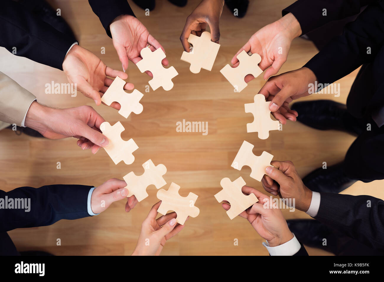 Directly above shot of business people joining jigsaw puzzle pieces in ...