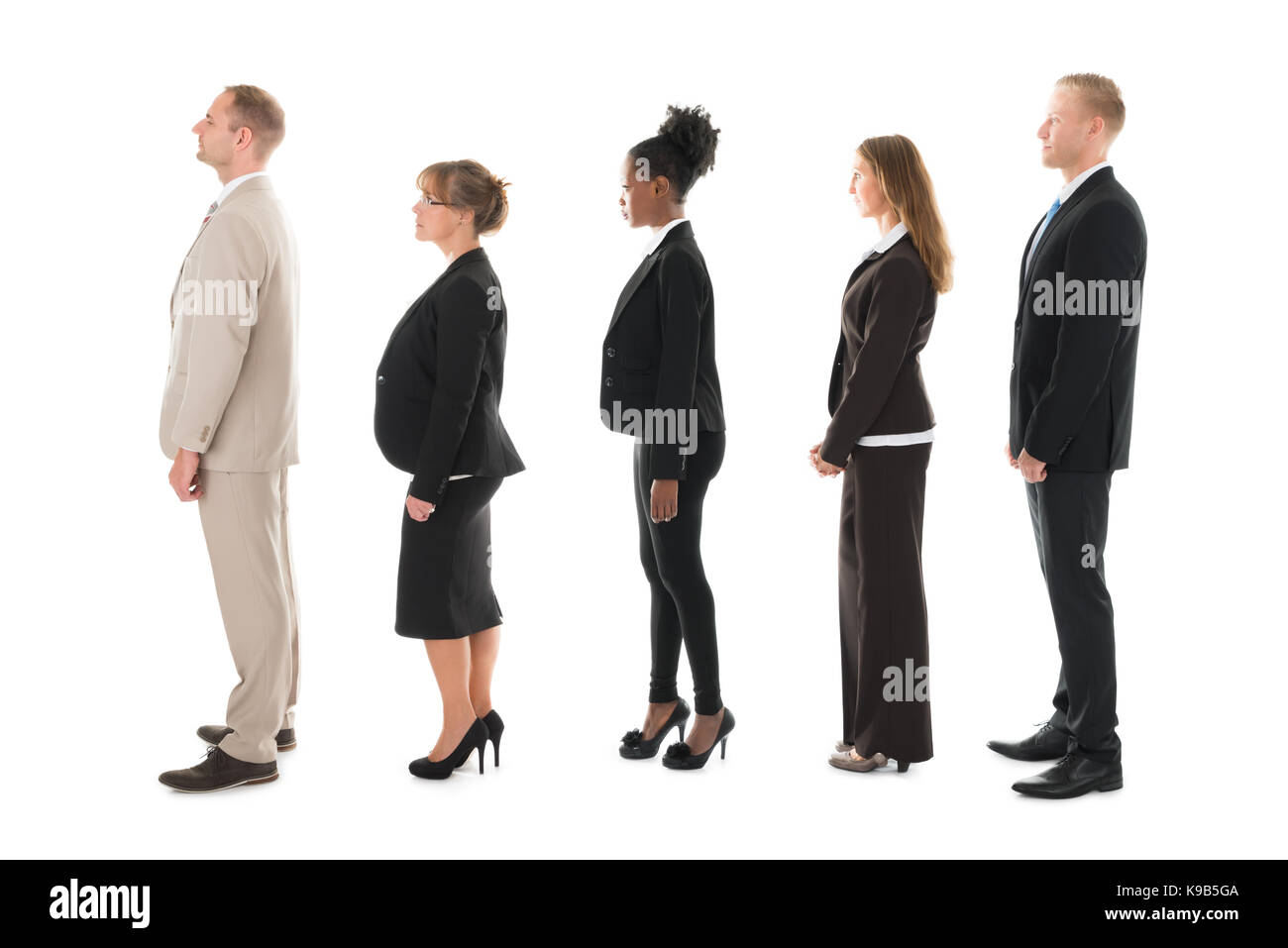 Full length side view of business team standing in row against white ...