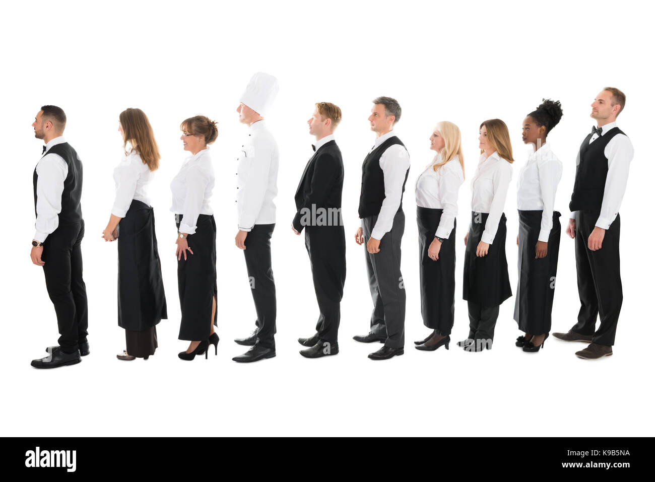 Full length side view of restaurant staff standing in line against ...