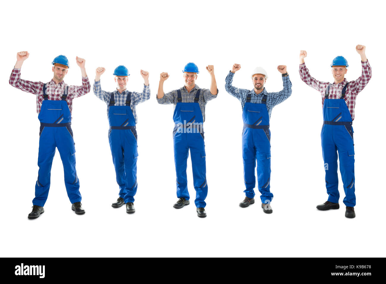 Full length portrait of successful carpenters with arms raised standing ...