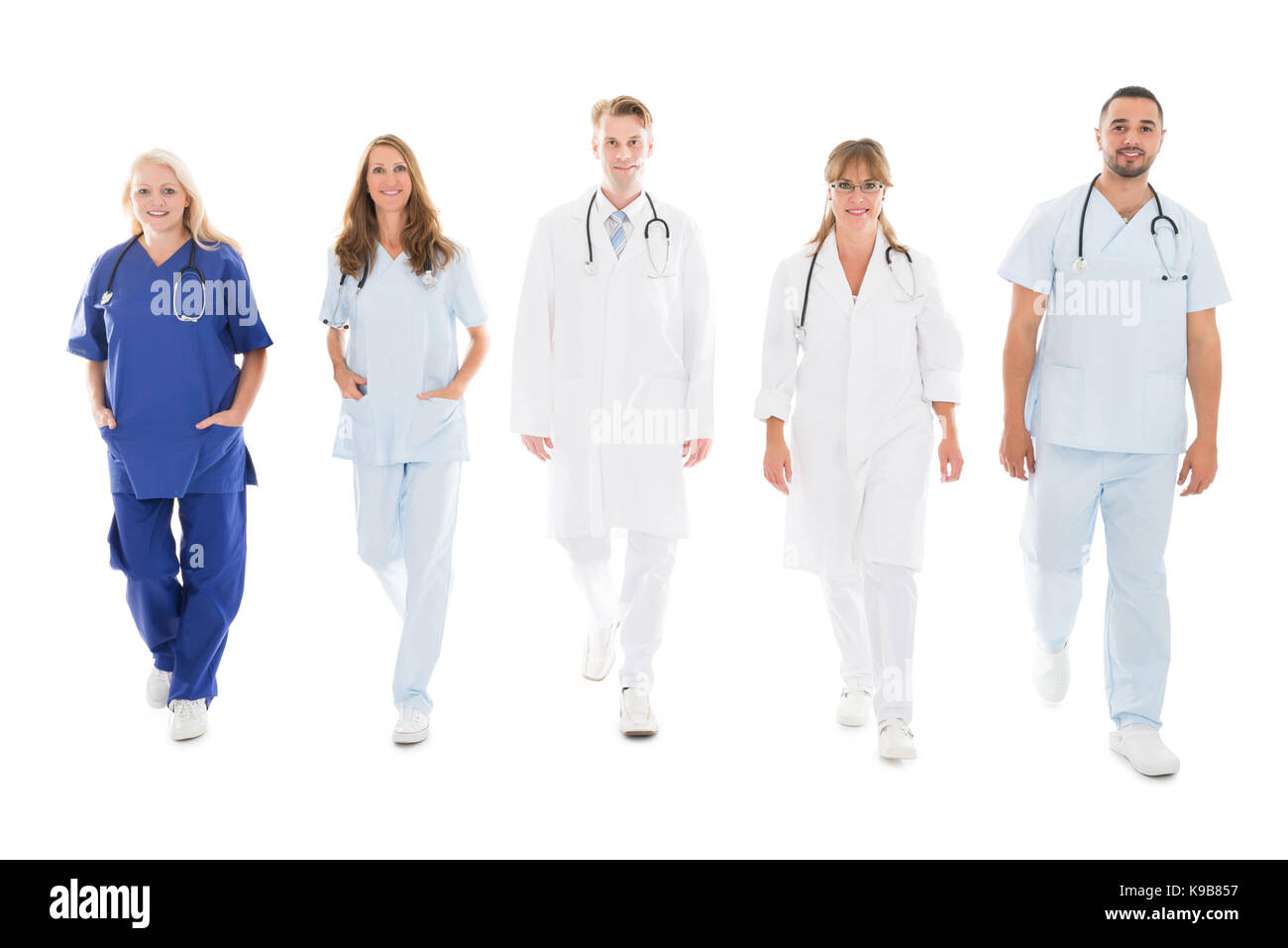 Full length portrait of confident medical team walking in row against ...