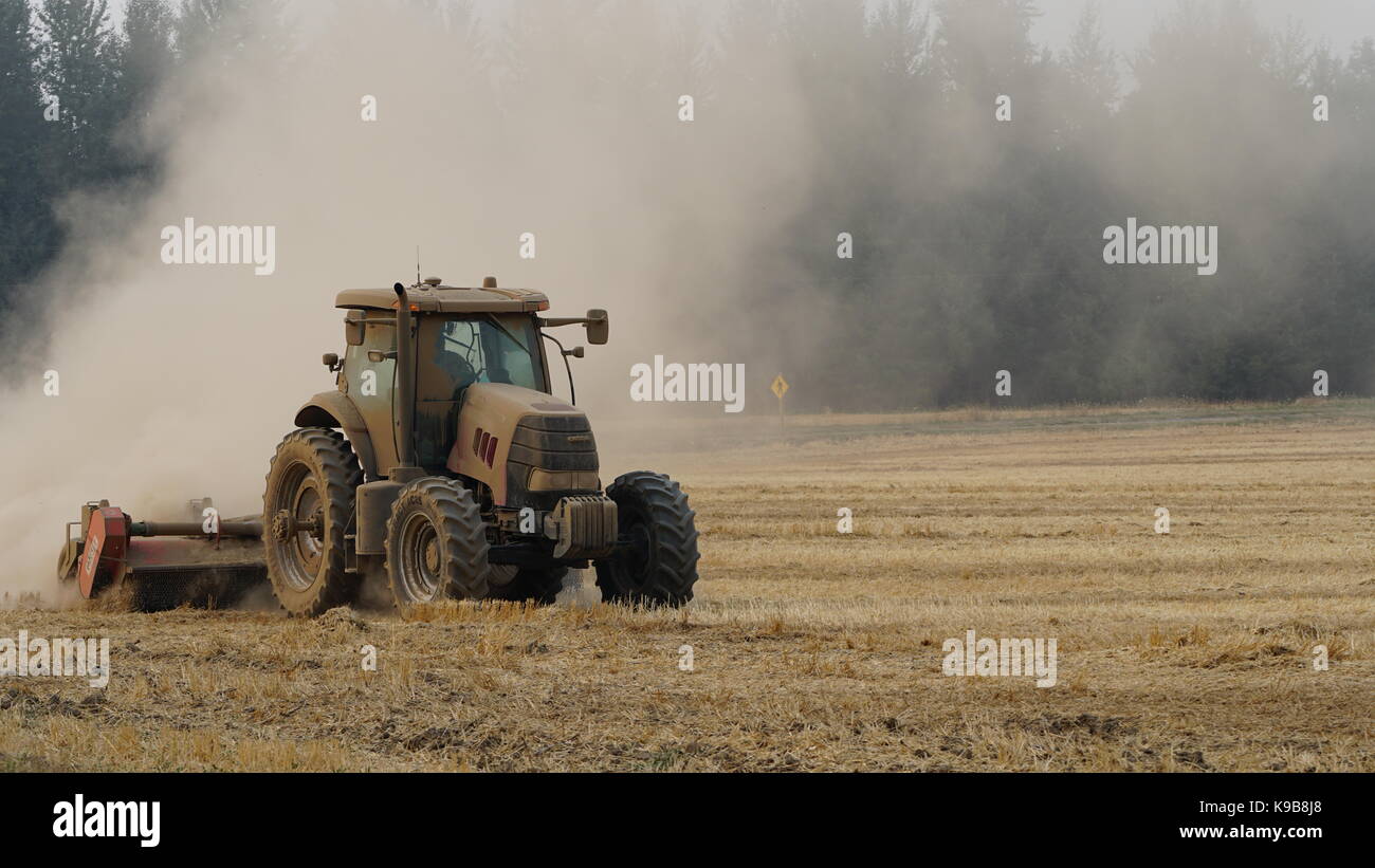 Heavy tractor dragging across dry soil Stock Photo - Alamy