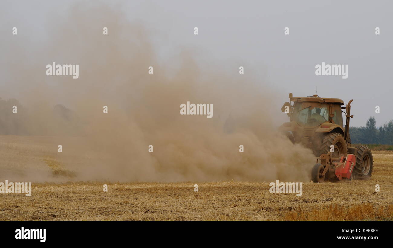 Heavy tractor dragging across dry soil Stock Photo - Alamy