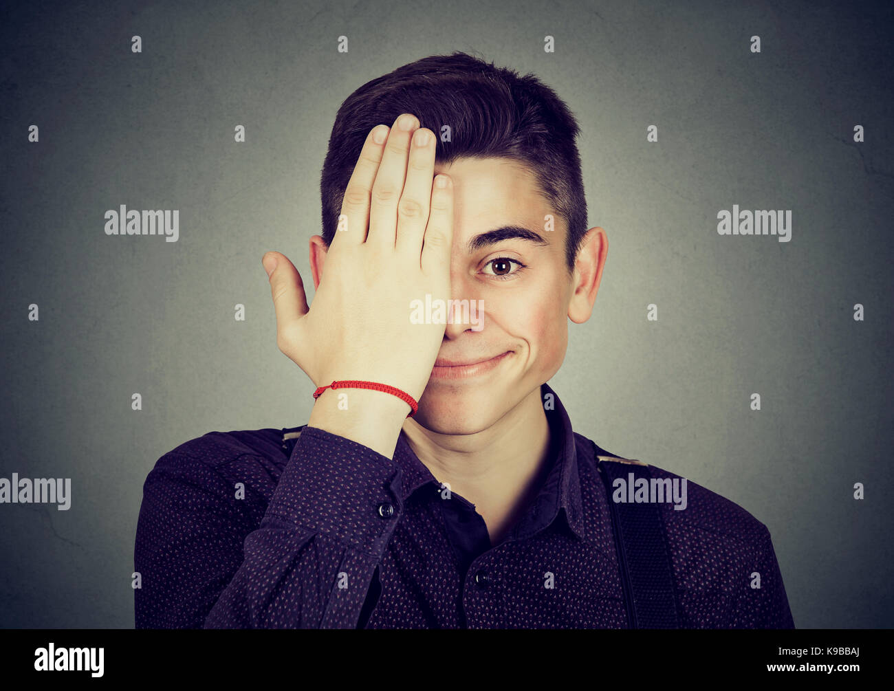 Happy young man with funny expression and hand over half face Stock ...