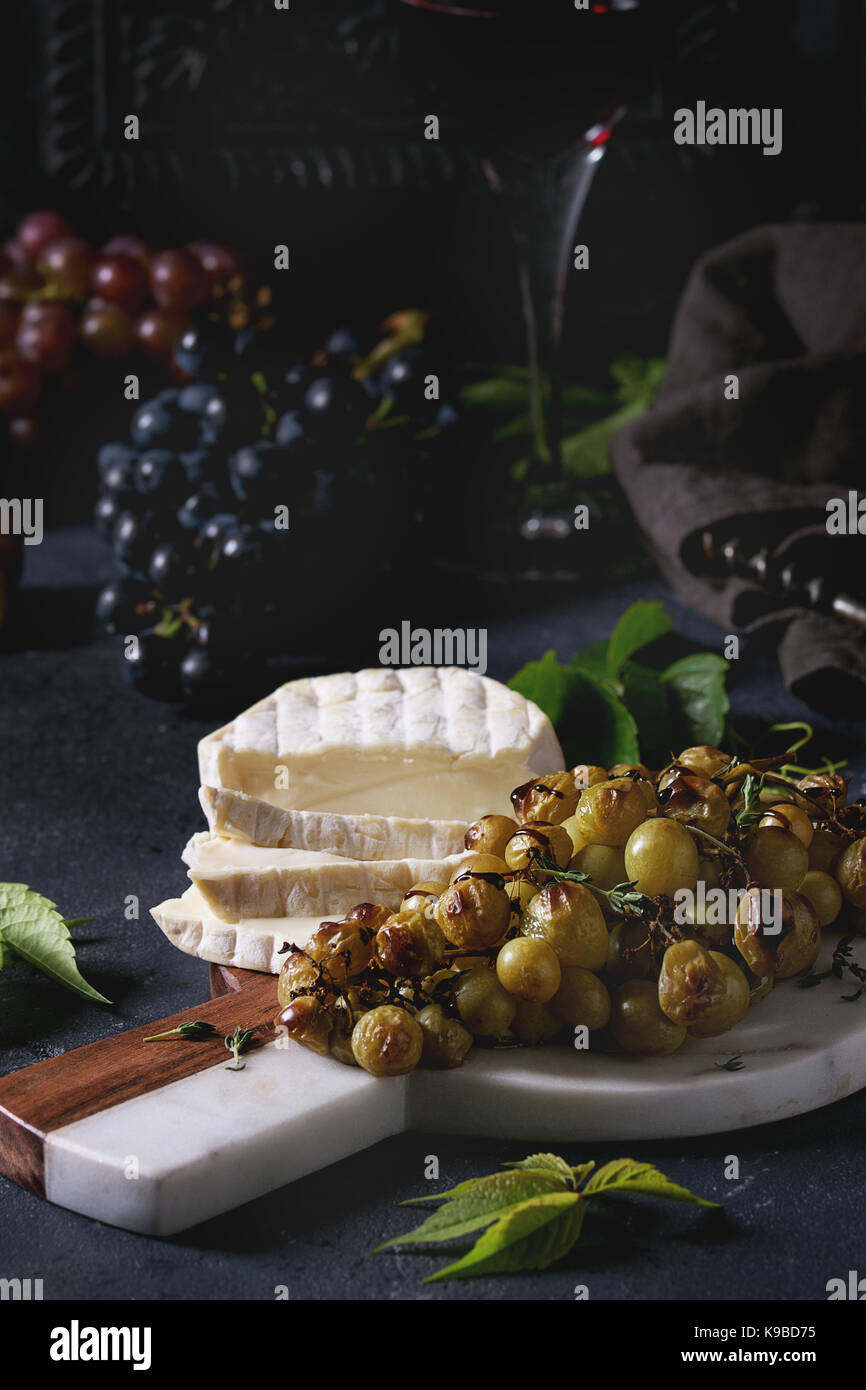 Serving board with sliced camembert cheese and baked bunch of green ...