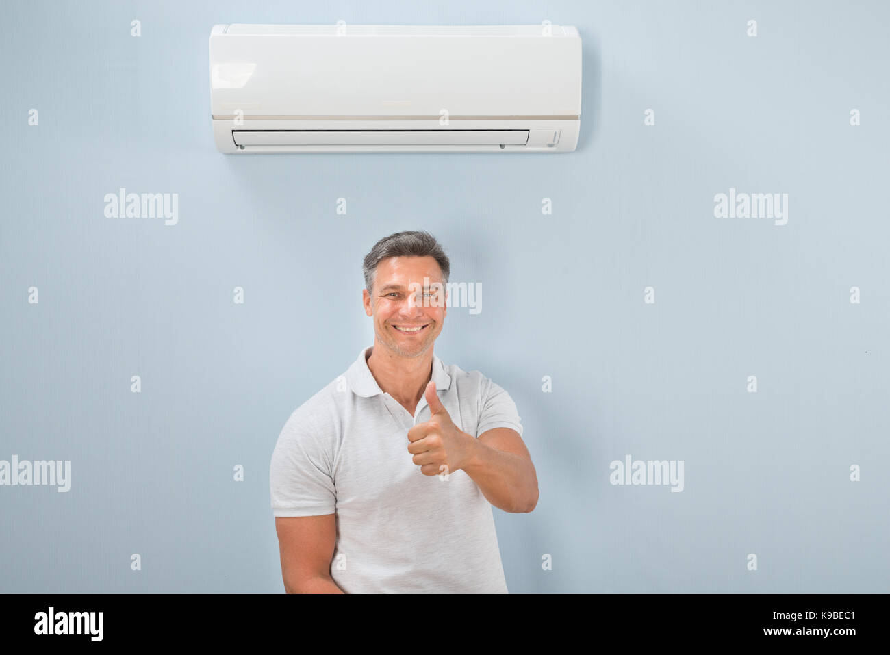 Portrait Of A Man Standing Under Air Conditioner Showing Thumb-up Sign ...