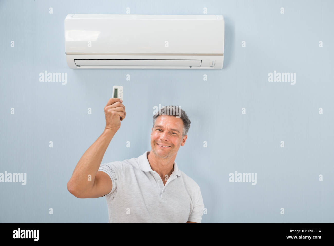 Portrait Of Mid-adult Man Using Air Conditioner Stock Photo - Alamy
