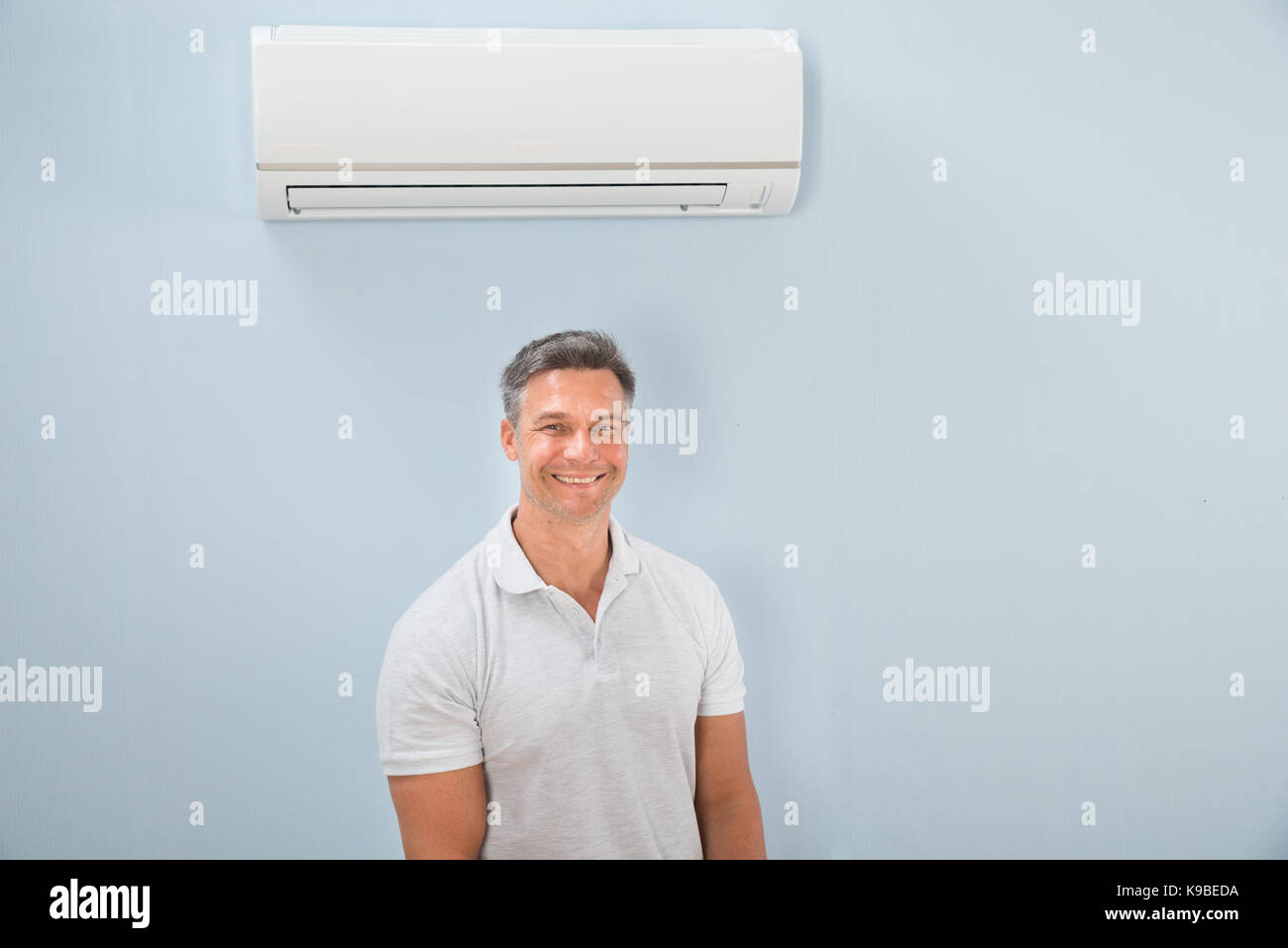 Portrait Of A Happy Mid-adult Man Standing Under Air Conditioner Stock ...