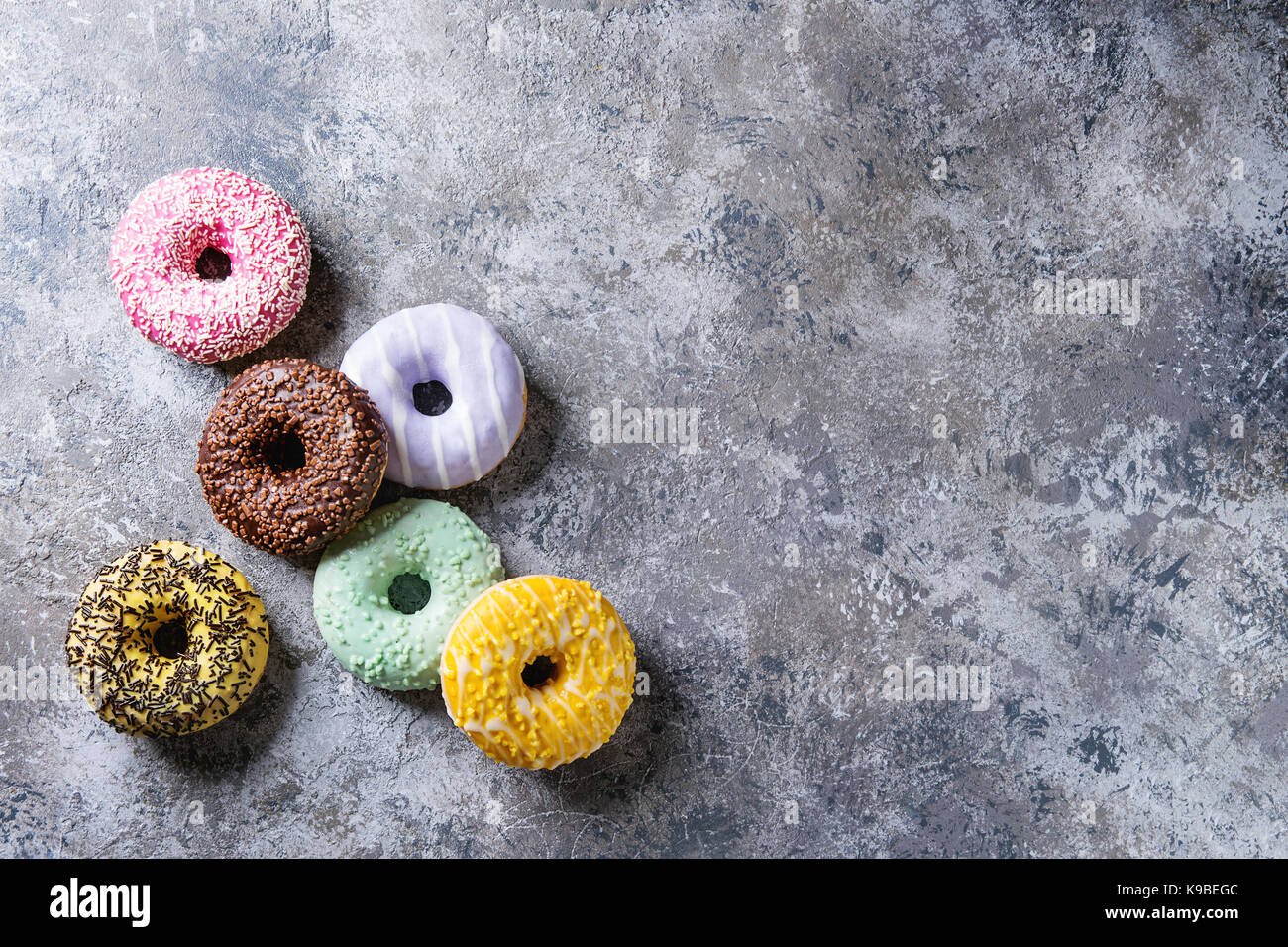 Variety of colorful glazed donuts over gray texture background. Top ...