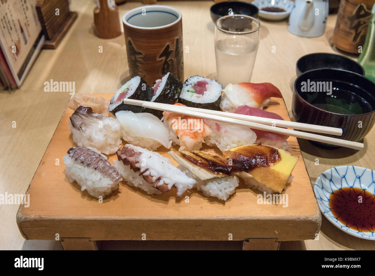 Sushi served on a wooden board with traditional Japanese accoutrements ...