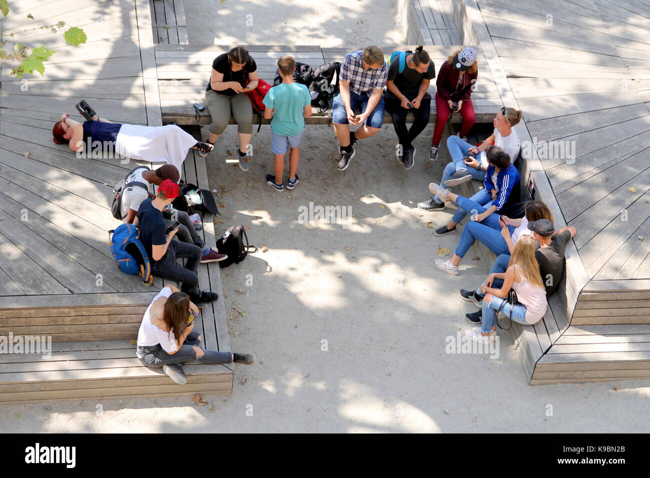 Overhead view of a group of teenagers relaxing on wooden benches ...