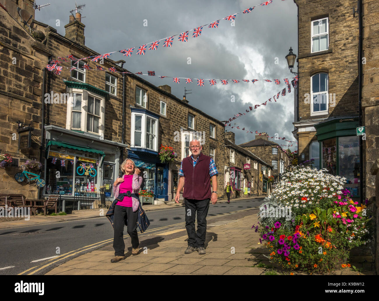 Two mature adults (70-80) walking the colourful High Street of Pateley ...