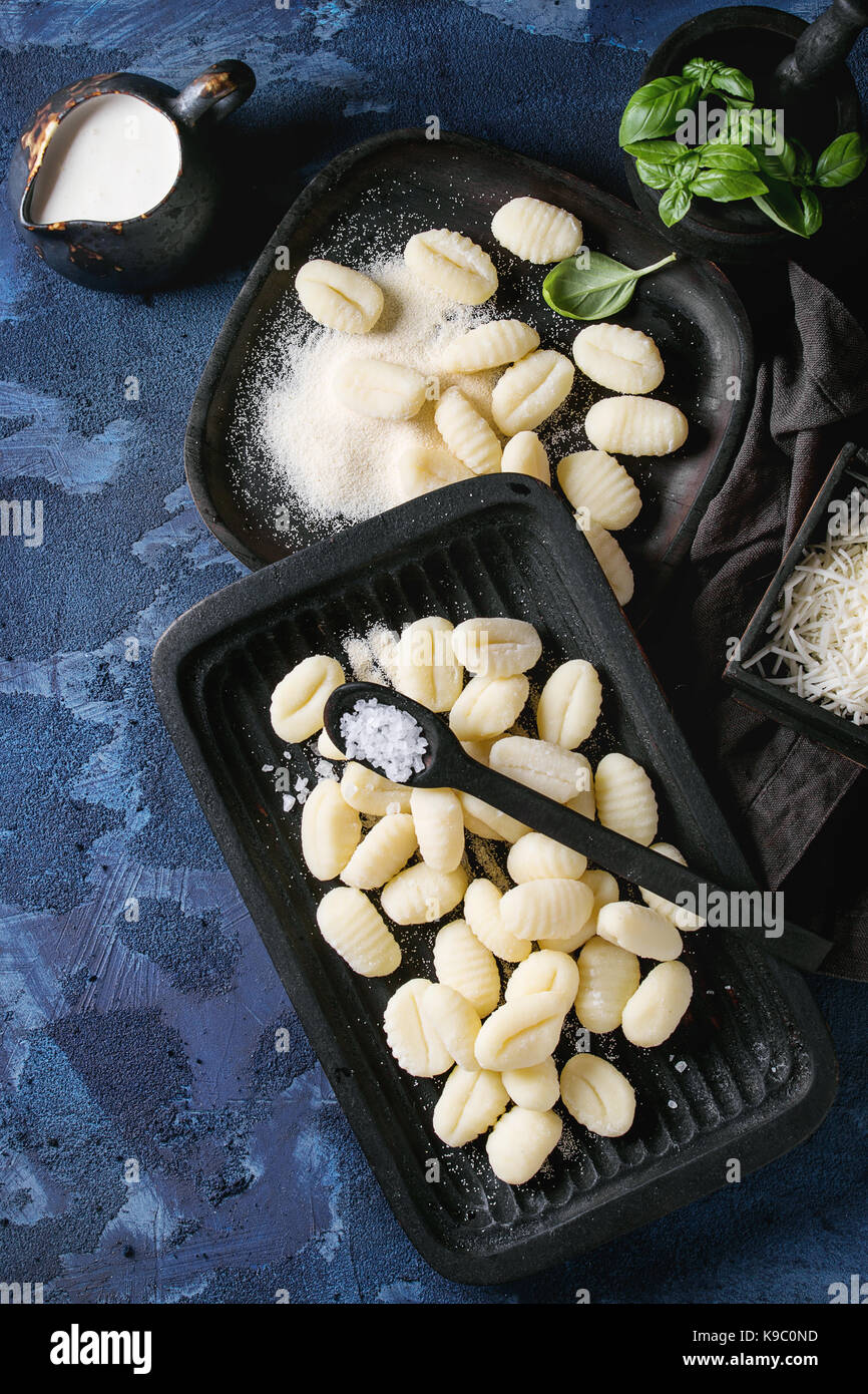 Raw uncooked potato gnocchi in black wooden plates with ingredients ...