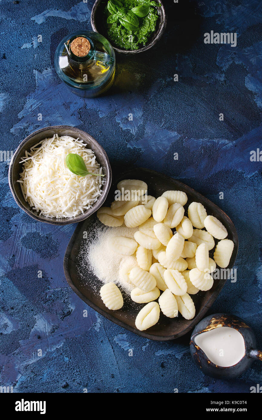 Raw uncooked potato gnocchi in black wooden plates with ingredients ...