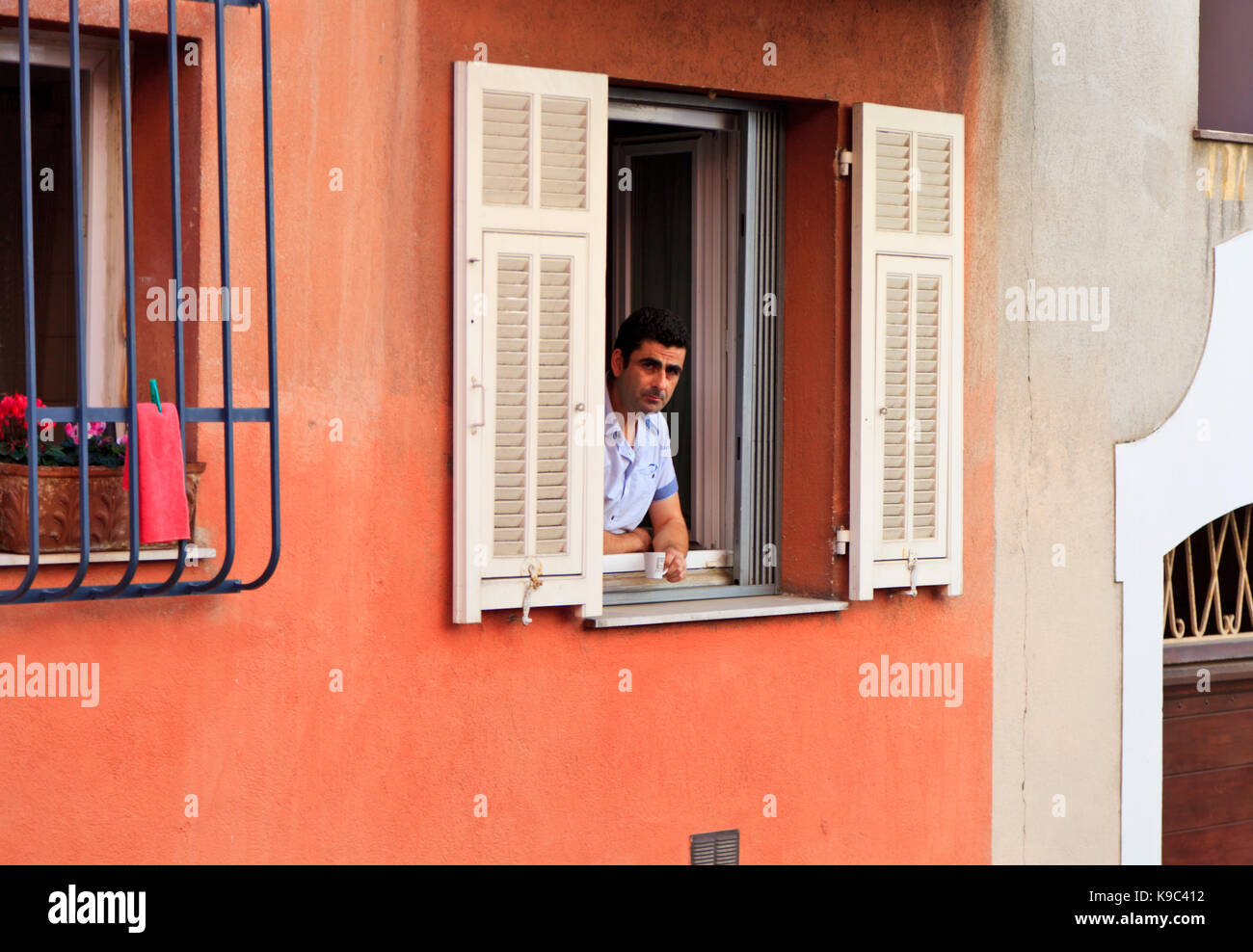 A man looking out of his window in the old town of Nice, France Stock ...