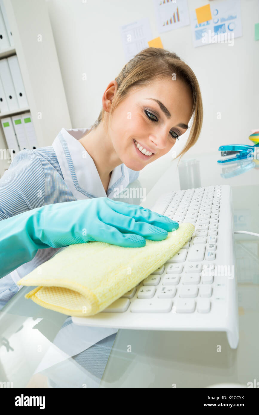 Portrait Of Young Happy Maid Cleaning Keyboard At Desk In Office Stock ...