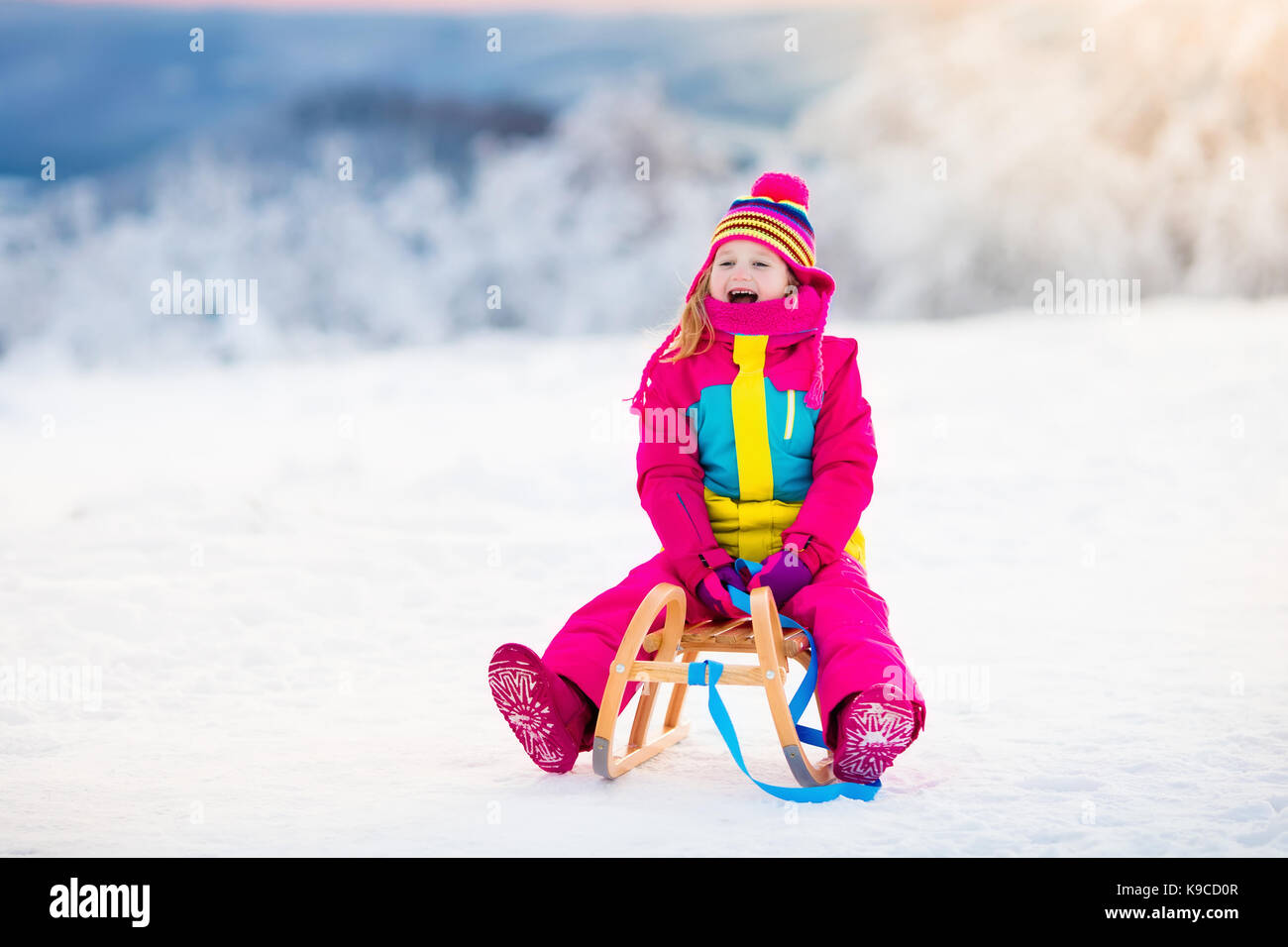 Little girl enjoying a sleigh ride. Child sledding. Toddler kid riding ...
