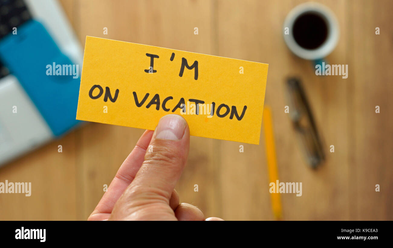 I'm on vacation written on a card holding in a hand at the office Stock ...