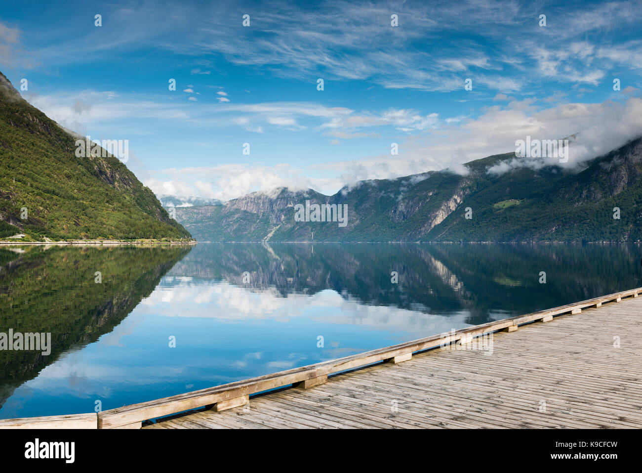 reflection of mountains in fjord in norway with wooden walking track in ...