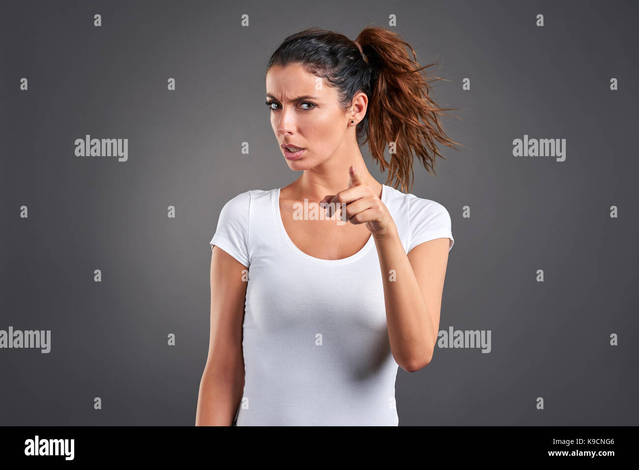 A beautiful young woman feeling suspicious and pointing in to the ...