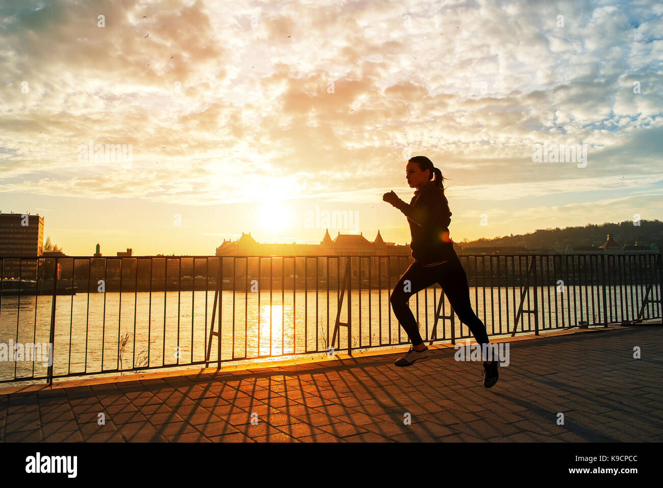 Silhouette of a beautiful young woman running in the sunset by the ...