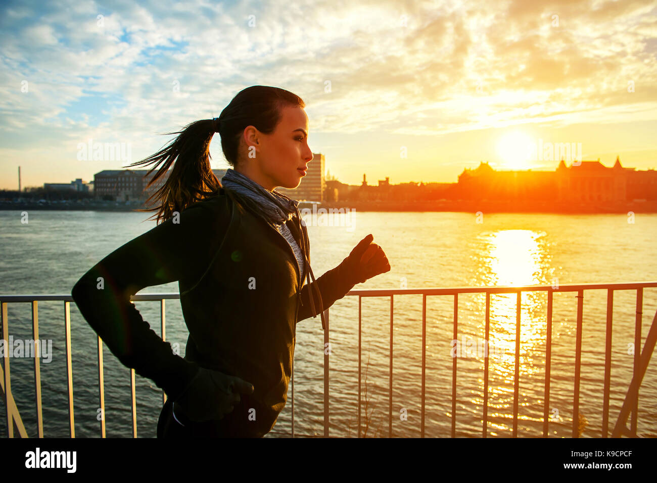Silhouette of a beautiful young woman running in the sunset by the ...