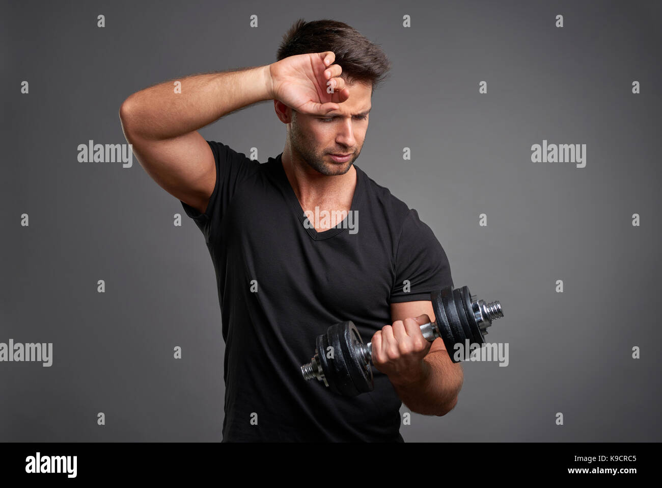 A handsome young man lifting weight and feeling tired Stock Photo - Alamy