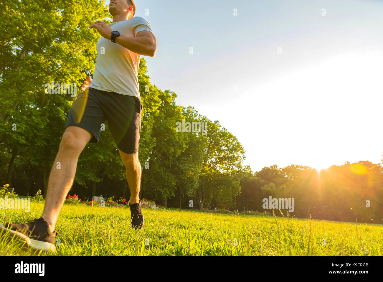 A handsome young man running on a summer evening in the sunset in a ...