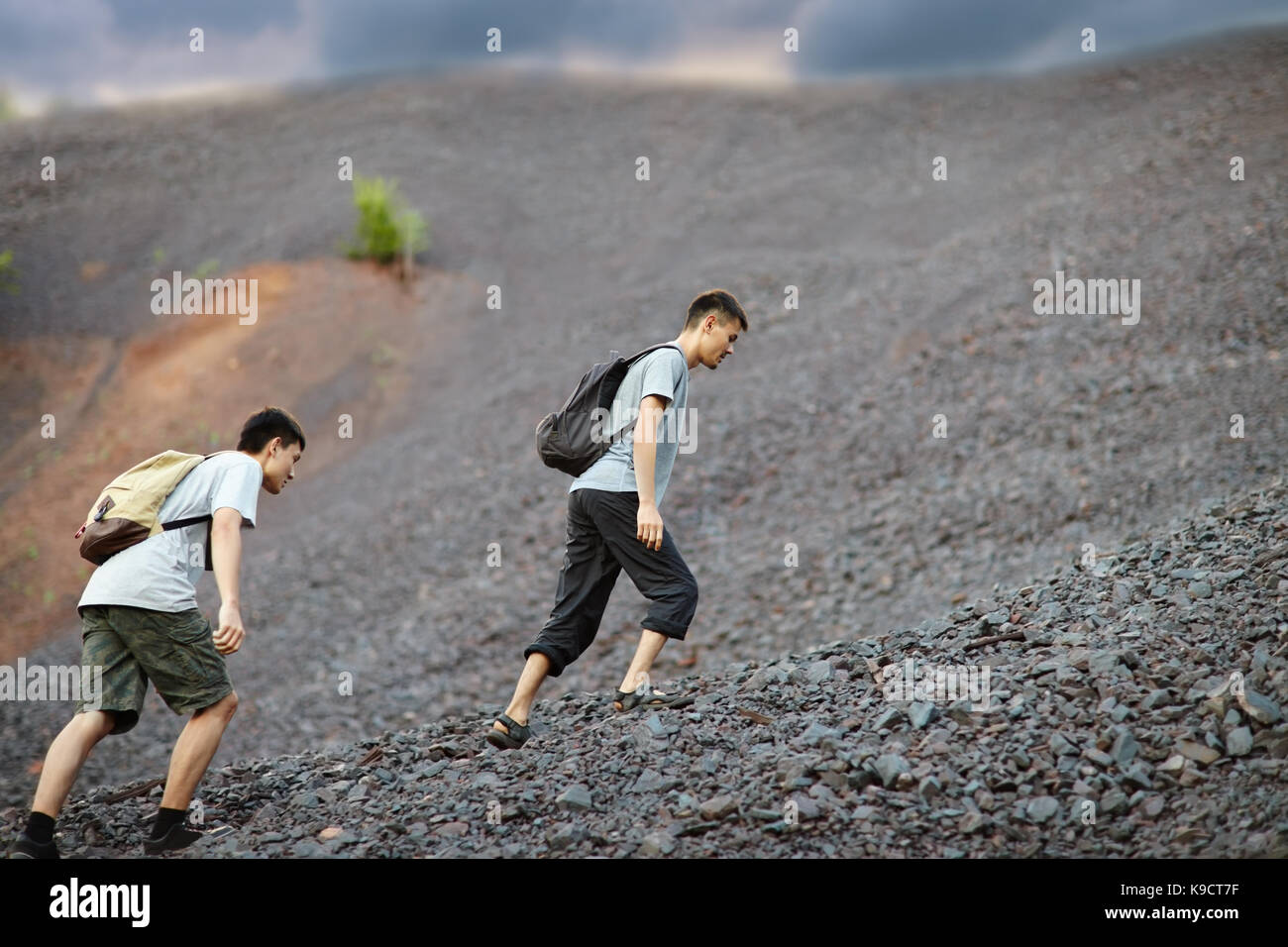 Two young tourist men walks on stones and rock slope Stock Photo - Alamy