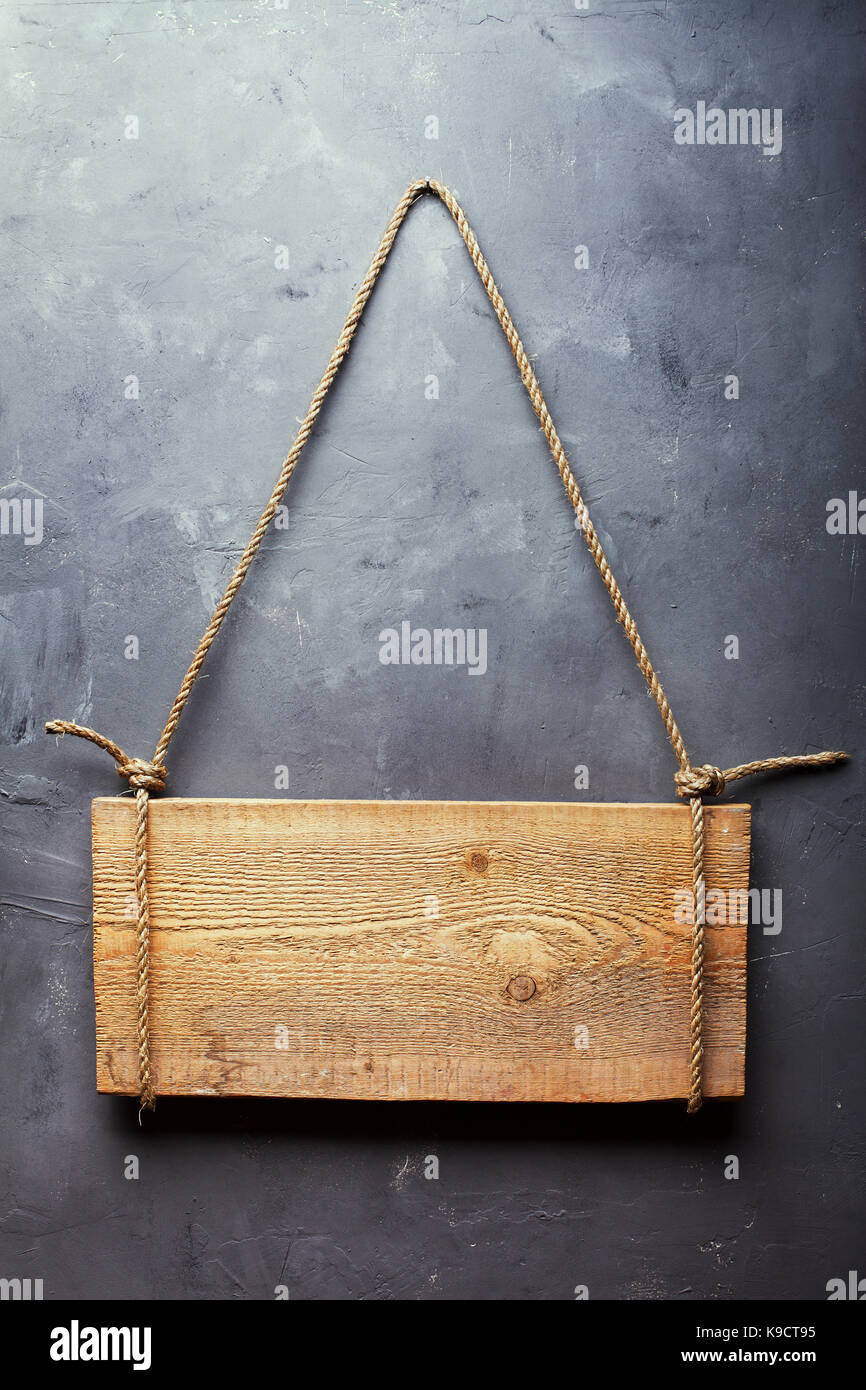 Wooden signboard hanging on rope on textured wall Stock Photo - Alamy