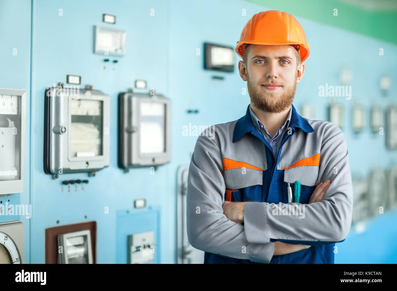 Portrait of young happy engineer at control room. Crossed arms Stock ...