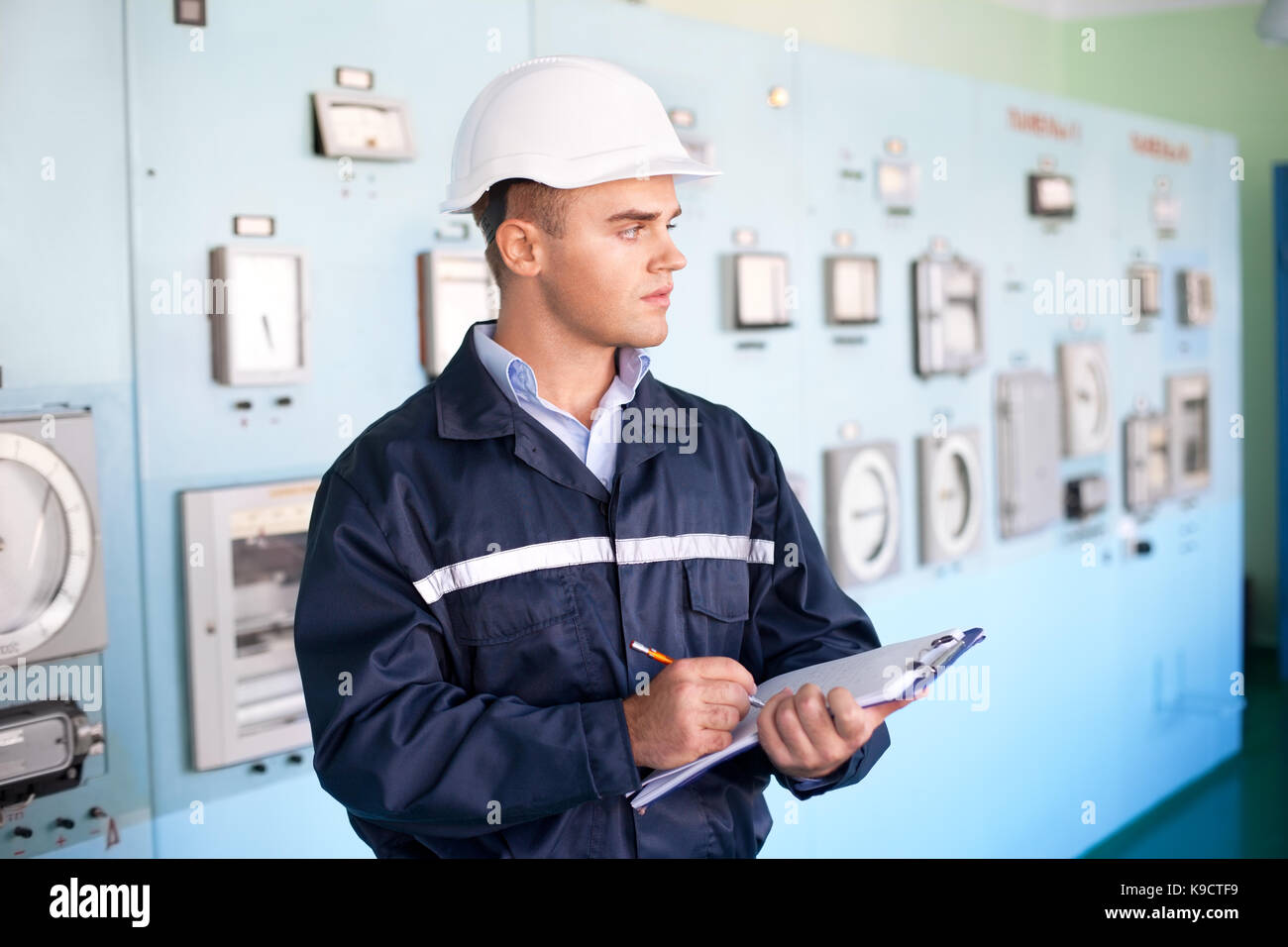 Portrait of young smiling engineer taking notes in control room Stock ...