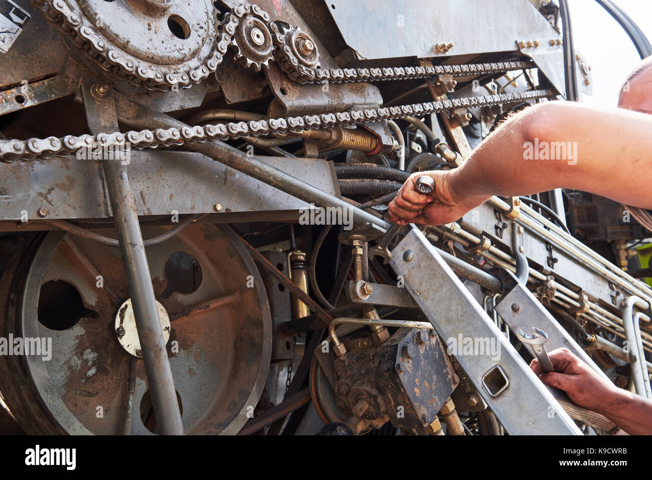 Combine machine service, mechanic repairing motor outdoors Stock Photo ...