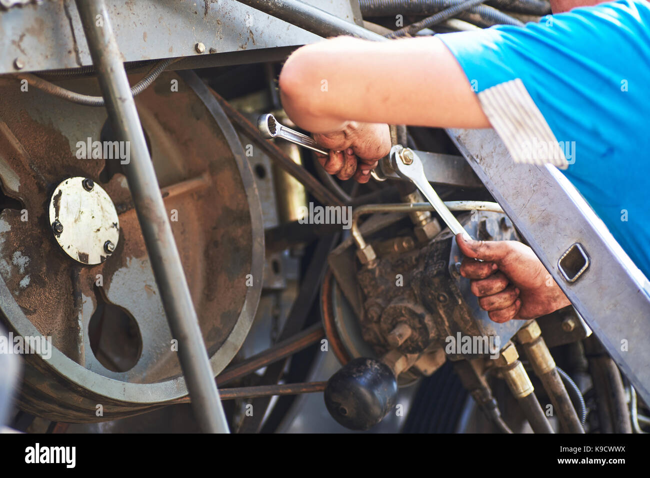 Combine machine service, mechanic repairing motor outdoors Stock Photo ...