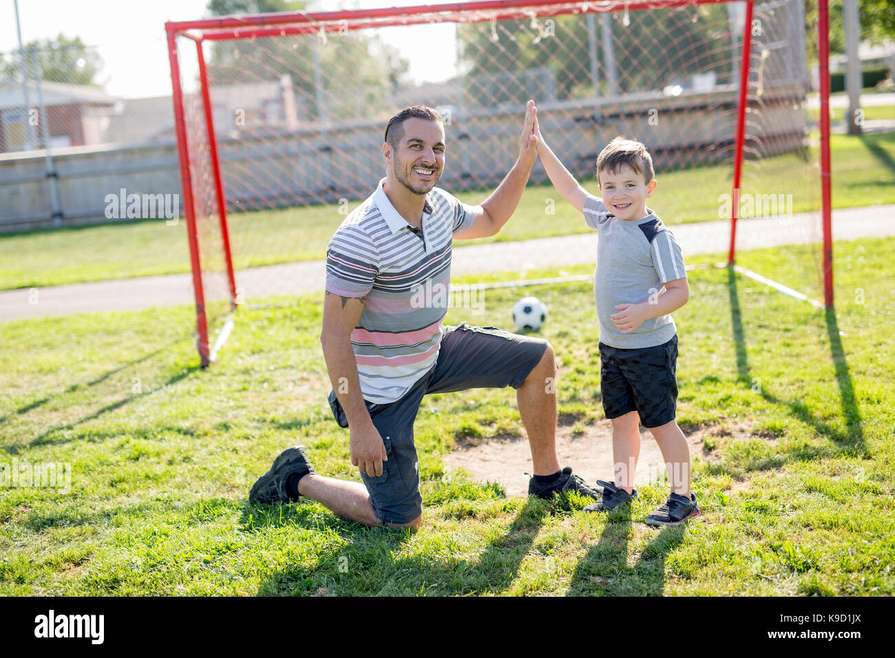 A man with child playing football outside on field Stock Photo - Alamy