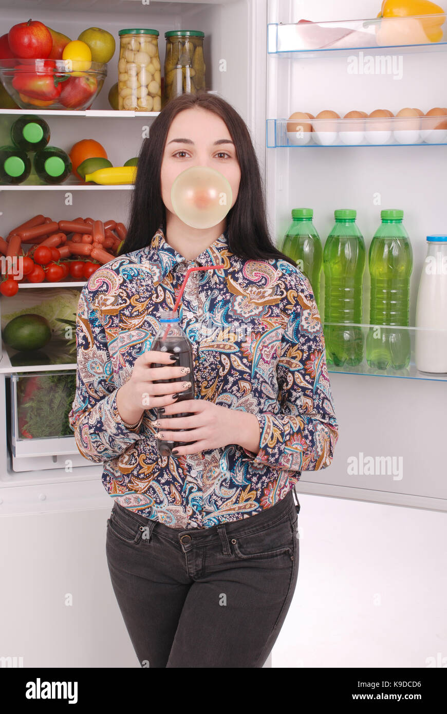 Young girl holding cola and making a big bubble with a chewing gum on ...