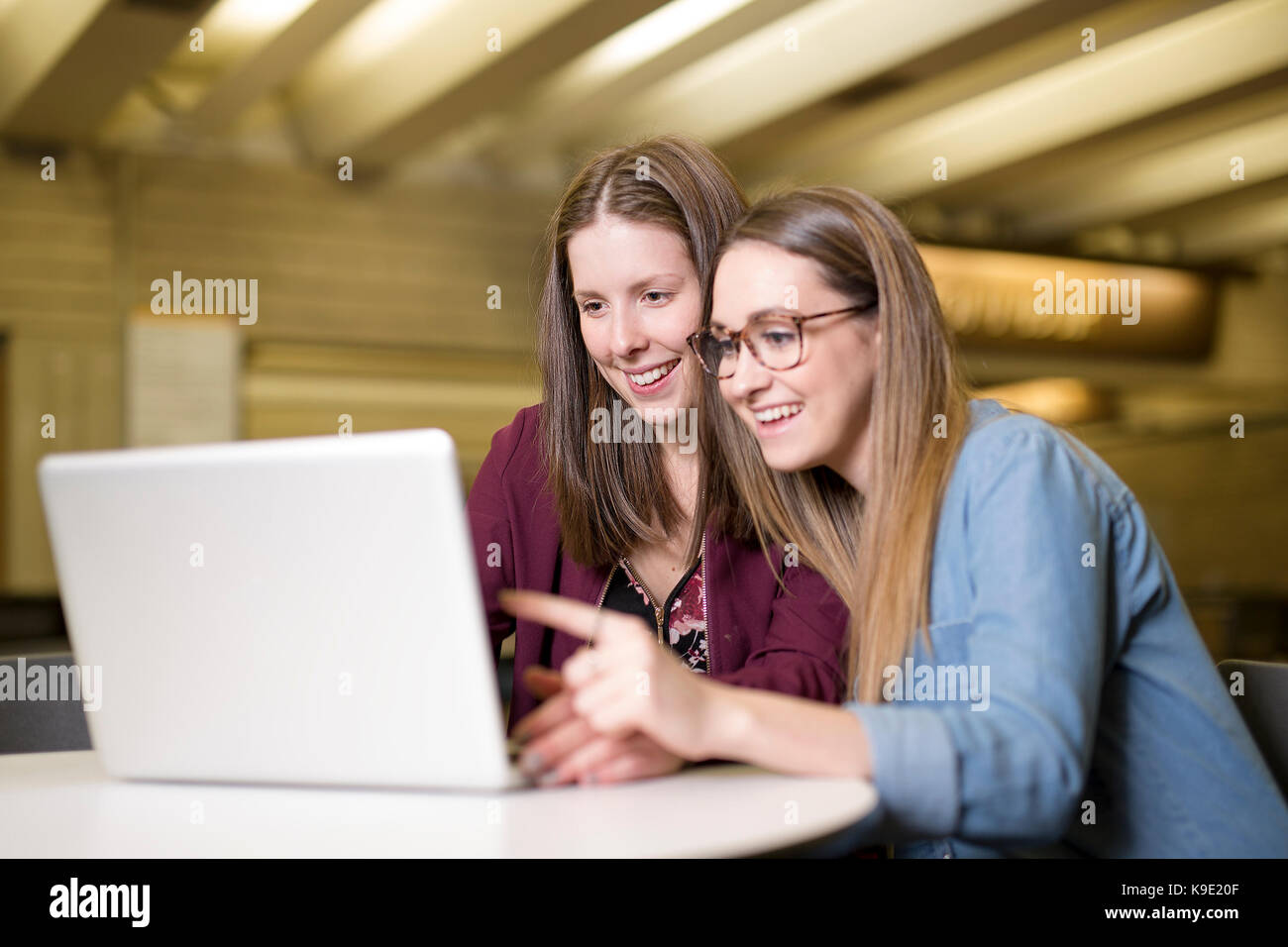 Two pretty female college student studying in the university library ...